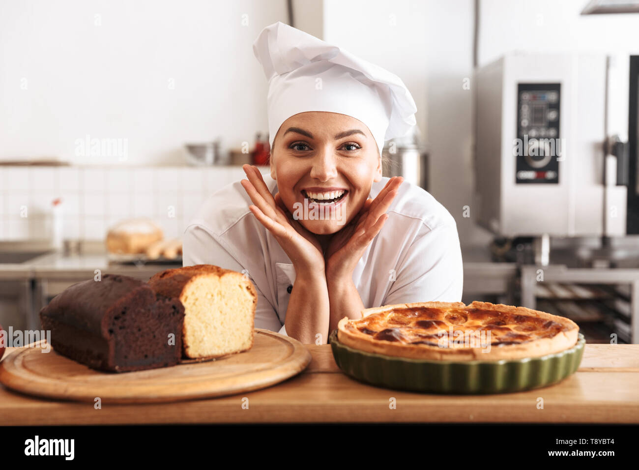 Image of adult woman chef wearing white uniform posing in kitchen at ...