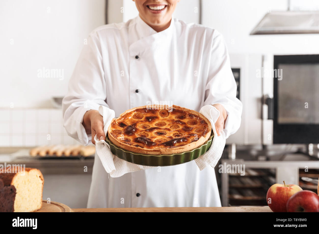 Image of smiling woman chef wearing white uniform holding apple pie ...