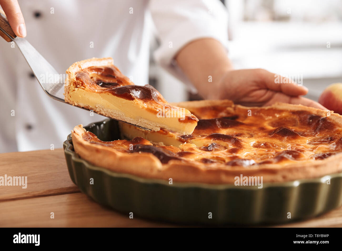 Image of successful woman chef wearing white uniform cutting apple pie ...
