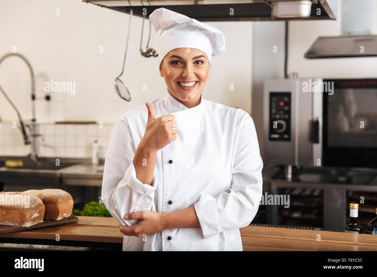 Portrait of european woman chef wearing white uniform posing in kitchen ...