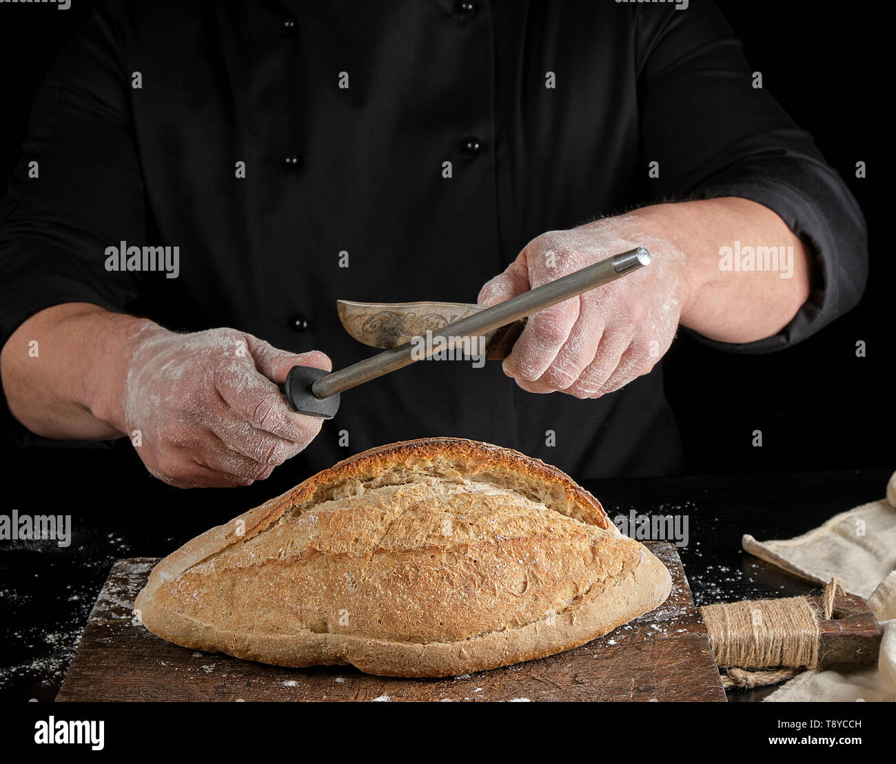 chef in black uniform sharpens a kitchen knife, next to it is baked ...