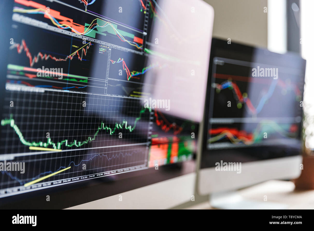 Photo of two computer screens with colorful graphics and charts ...