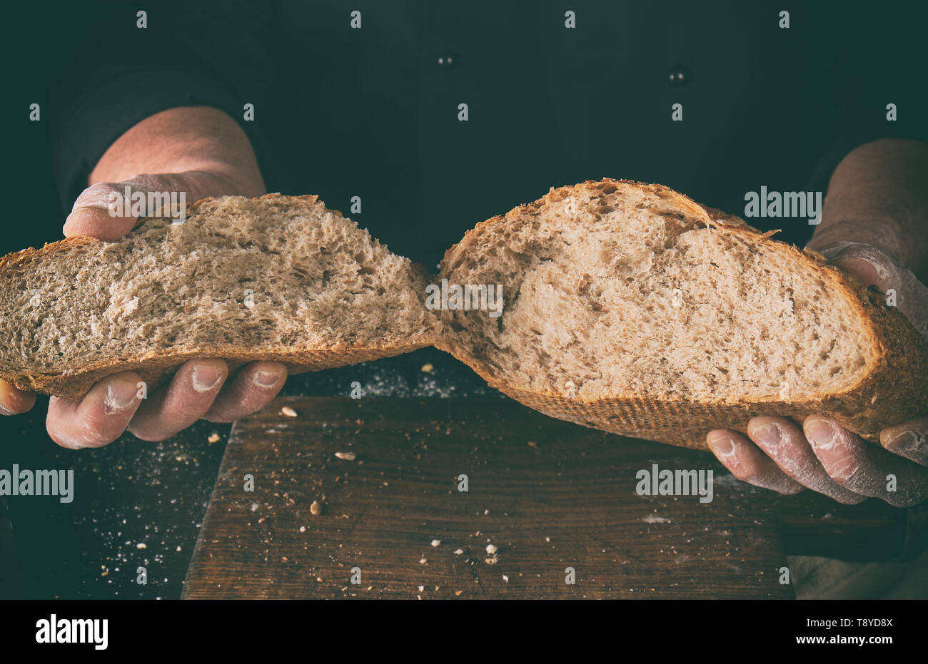 chef in black uniform holds in his hands half of broken off crusty ...