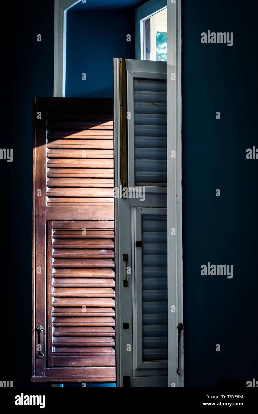 Shuttered window with one pane open letting through rays of light ...