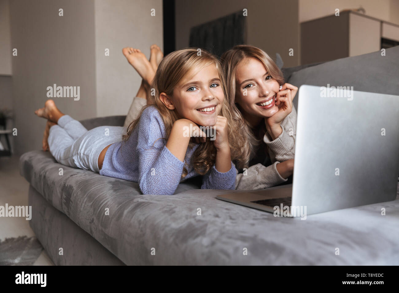 Photo of a young woman with her little sister indoors at home using ...