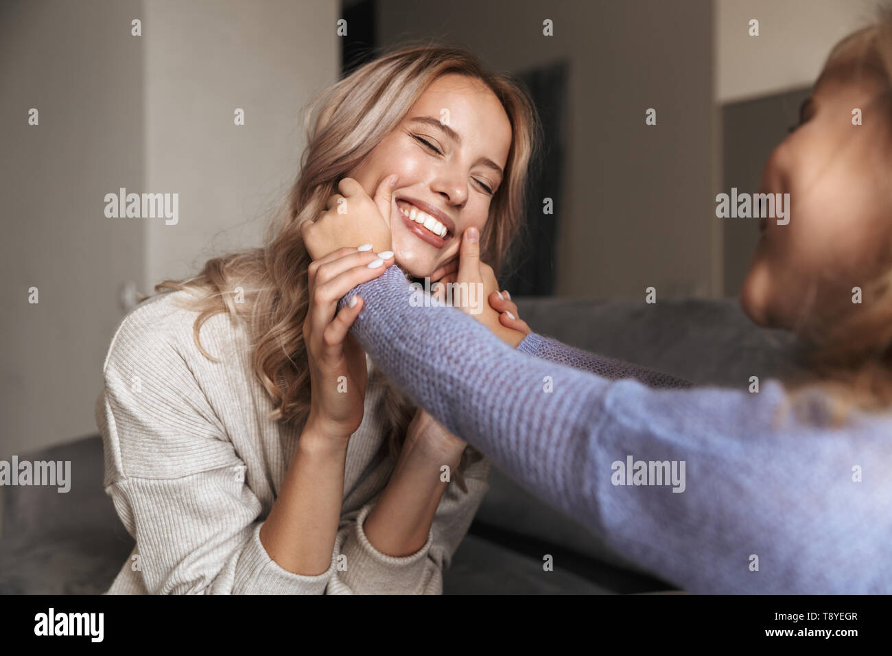 Image of two scared girls sisters on sofa at home indoors having fun ...