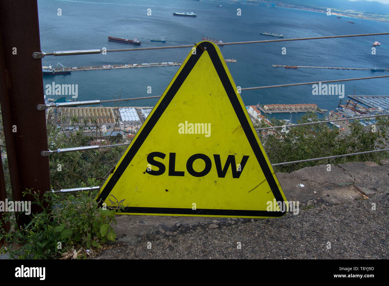 Slow sign on Gibraltar rock overlooking the sea triangle painted yellow ...