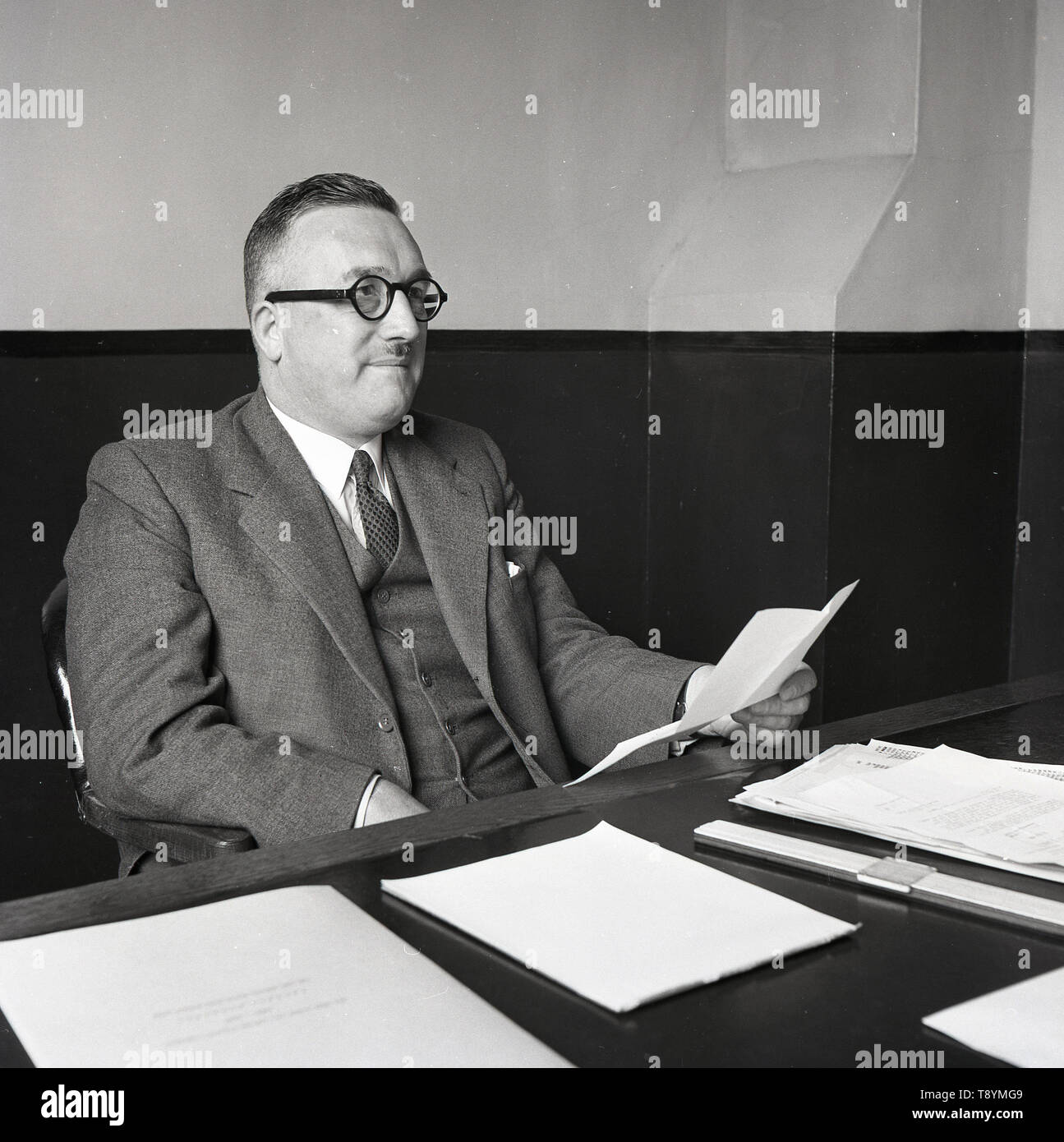 1950s, historical, suited manager of a factory sitting at his desk with ...