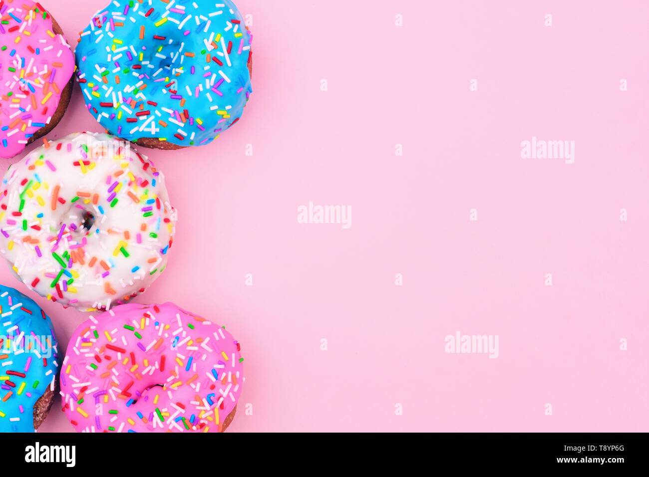 Side border of assorted donuts with frosting and sprinkles against a ...
