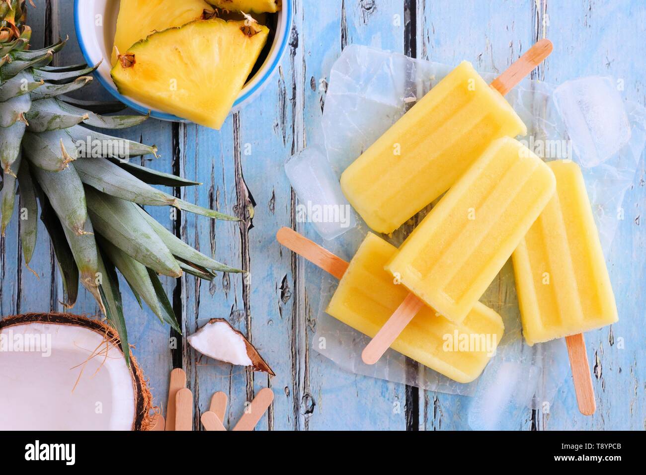 Pineapple coconut popsicles in a cluster. Top view scene over a blue ...
