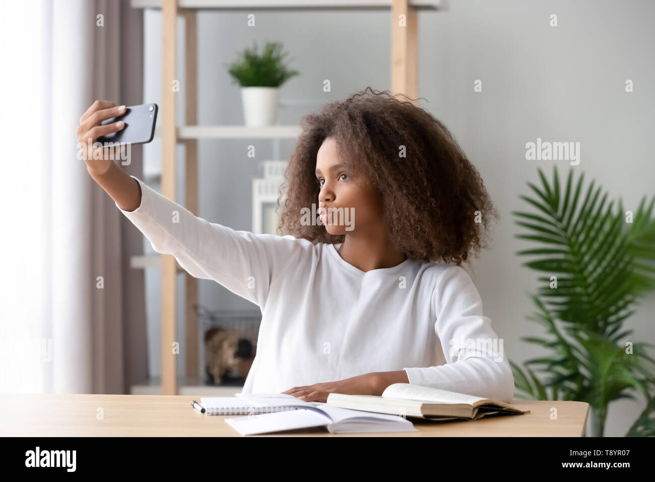African American teenage girl taking selfie during homework preparation ...
