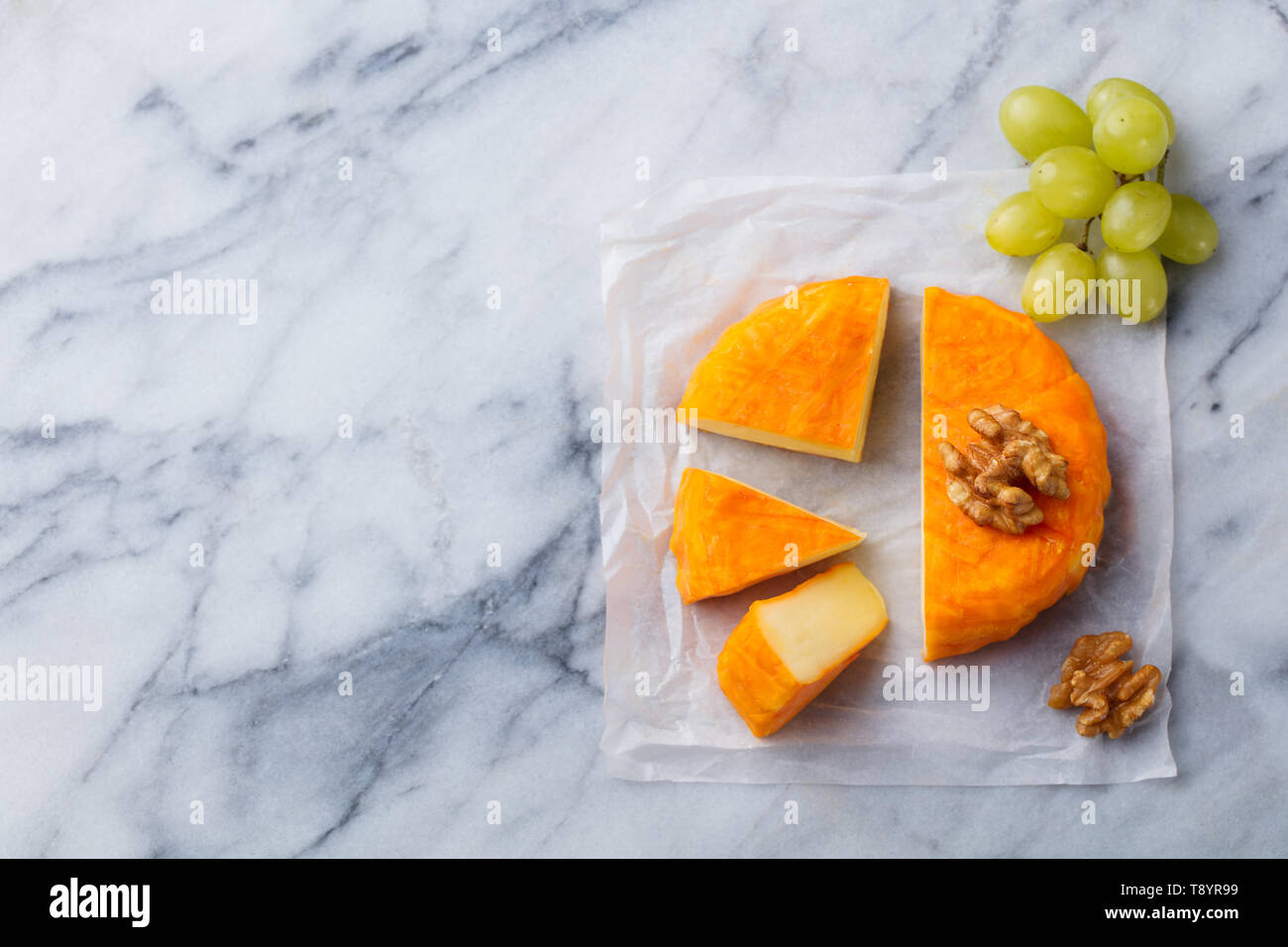 Cheese with washed orange rind and fresh grape. Marble background. Top ...
