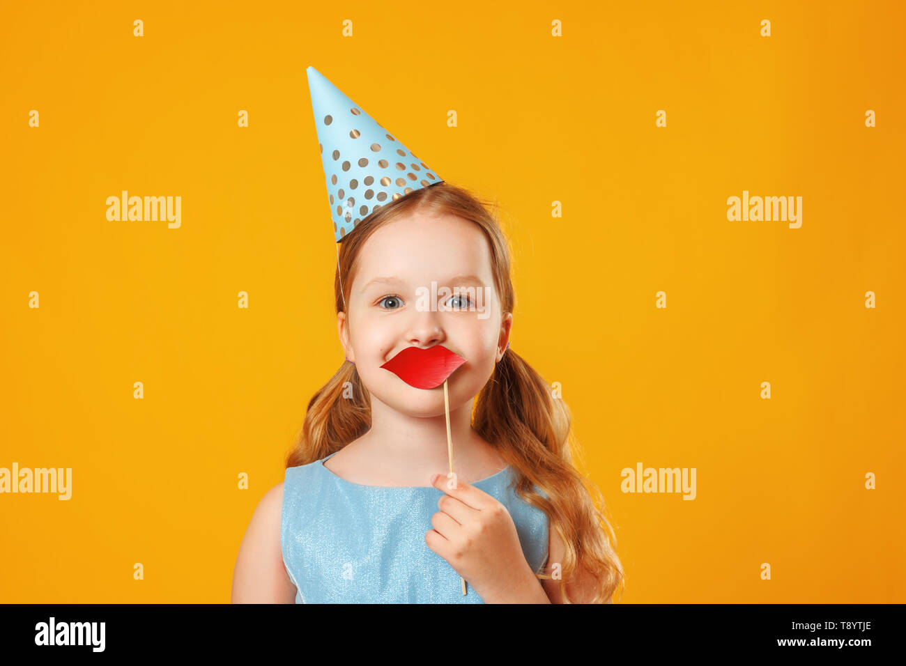 Funny little girl with fake lips on a yellow background. A party. Props ...