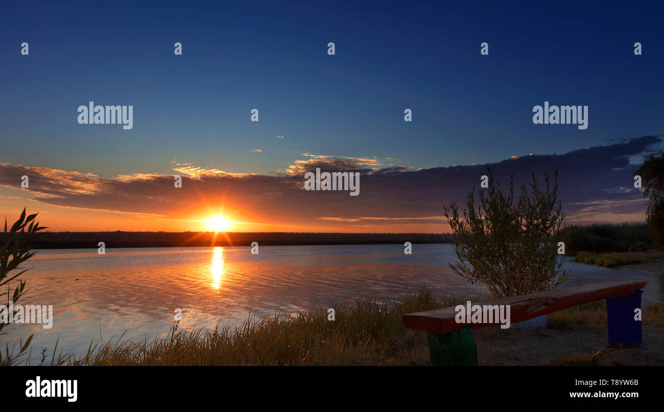 The bright rising sun illuminates the coastal grass, an old wooden ...