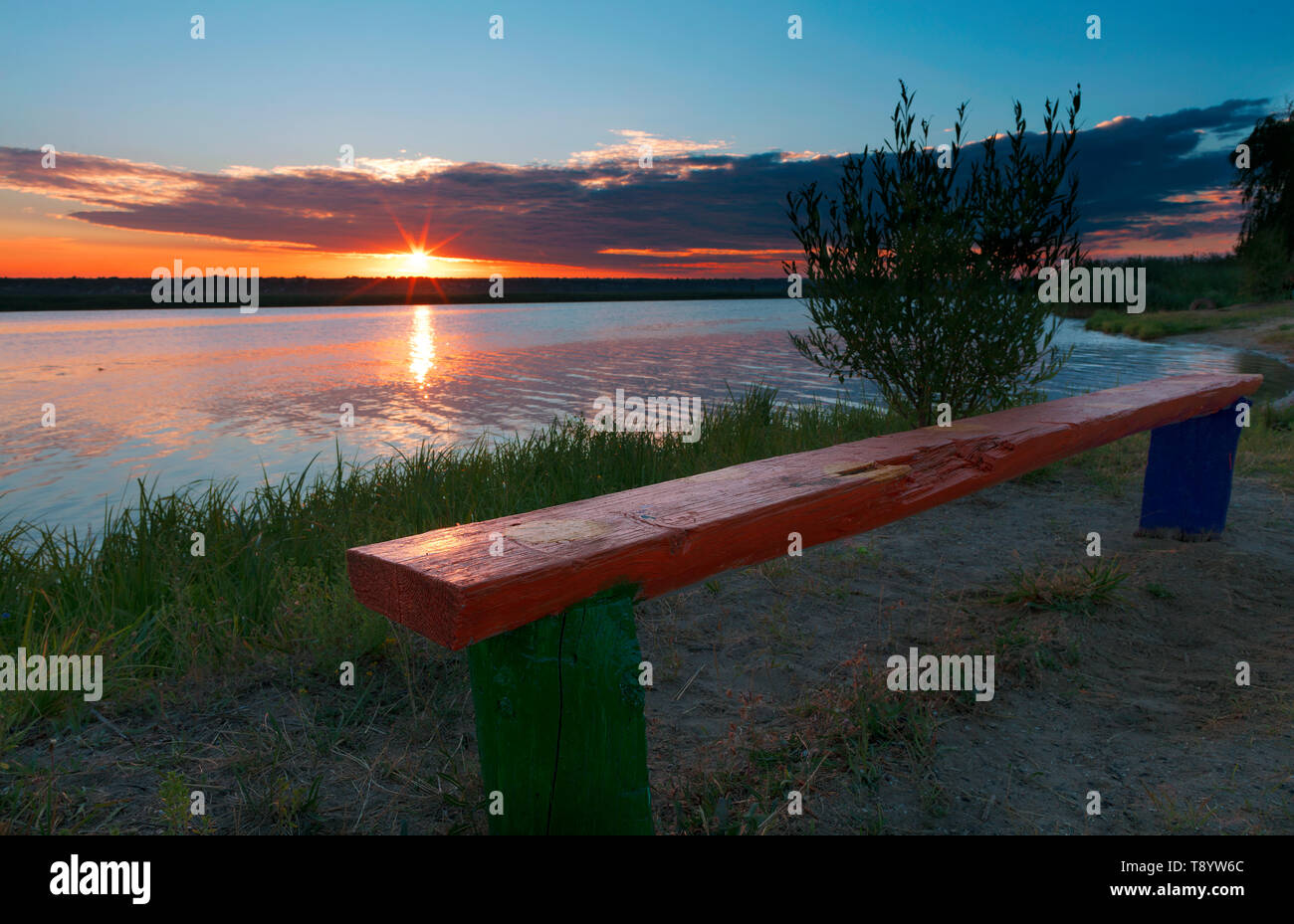 The bright rising sun illuminates the coastal grass, an old wooden ...