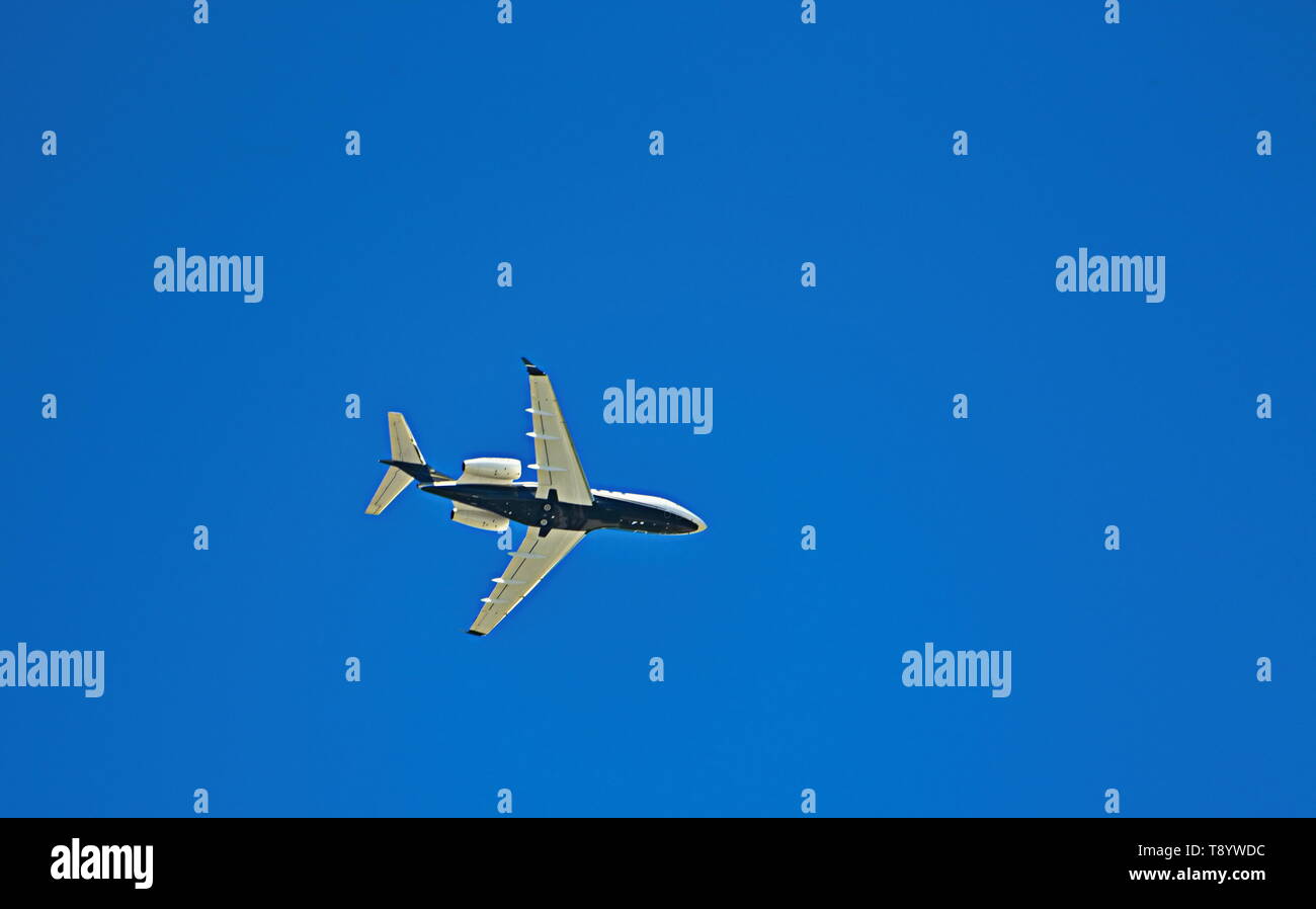 A Blue and White Passenger Jet from Below Under Blue Skies Stock Photo ...
