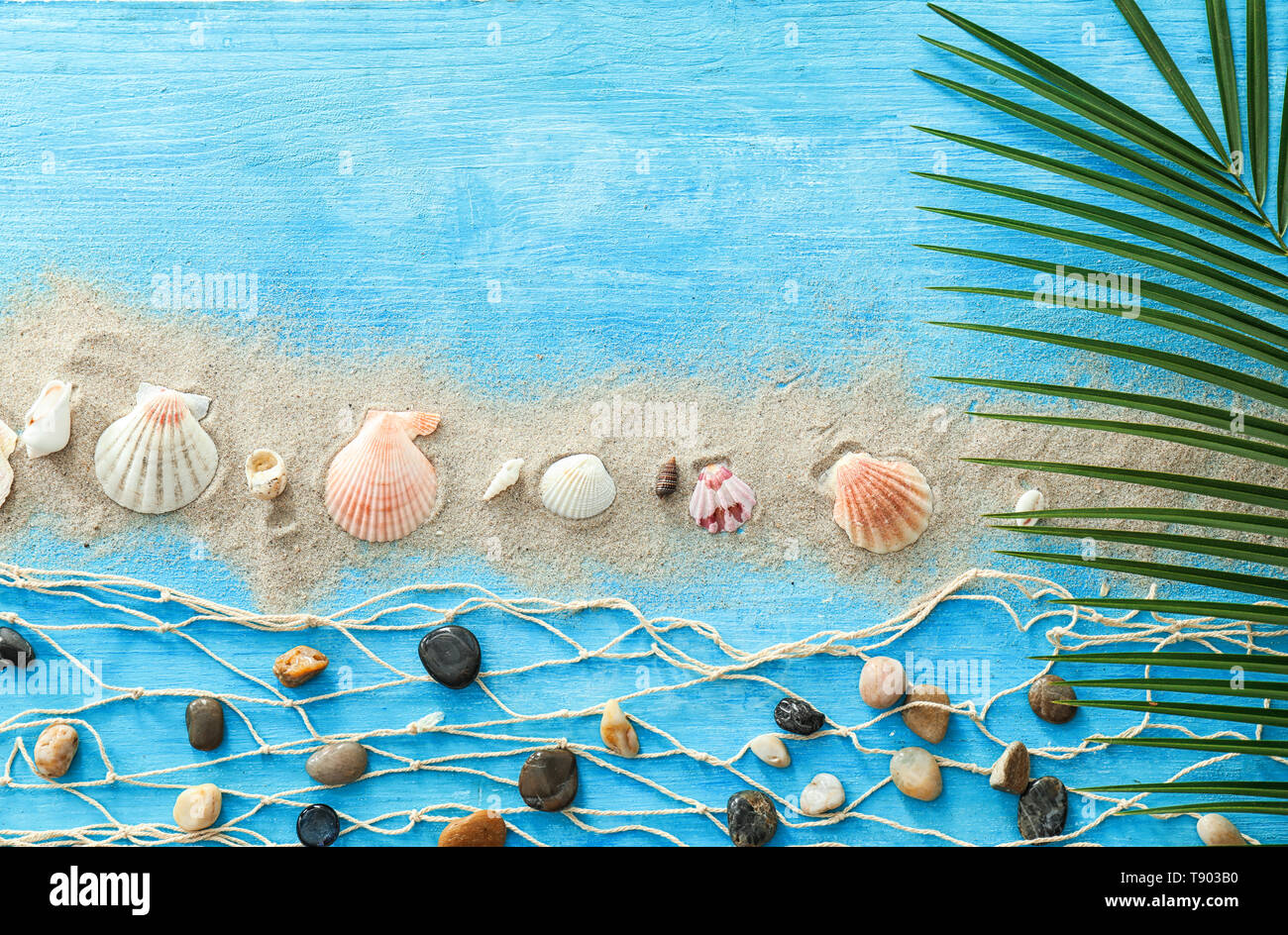 Composition with different sea shells and palm leaf on color wooden ...
