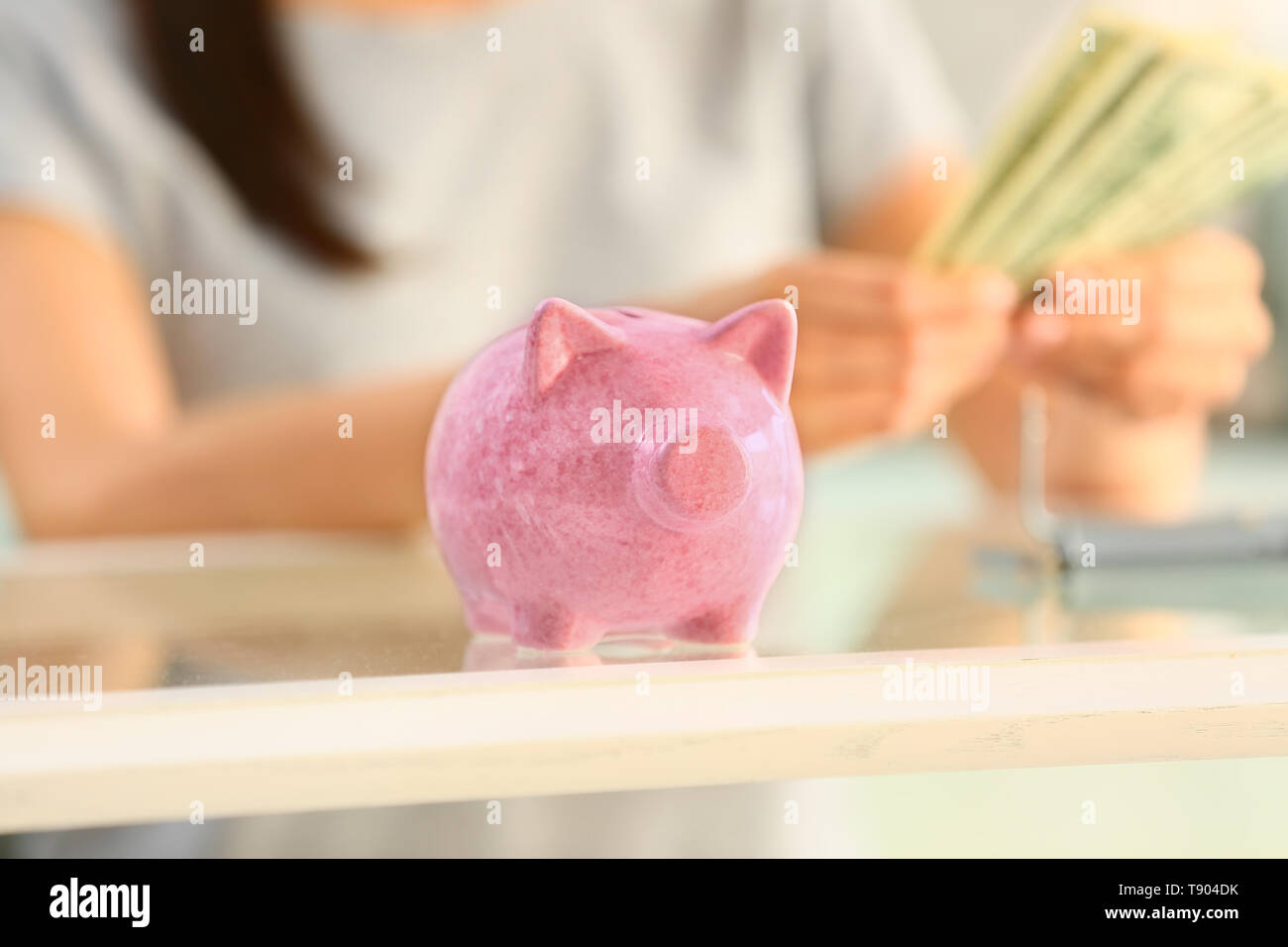 Cute piggy bank on table of woman counting money Stock Photo - Alamy