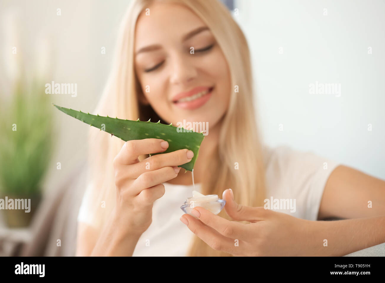 Beautiful young woman using cream with aloe vera extract at home Stock ...