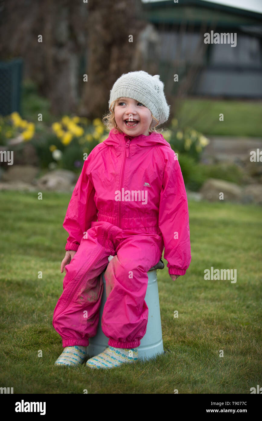 Little girls sitting on bucket in garden Stock Photo - Alamy