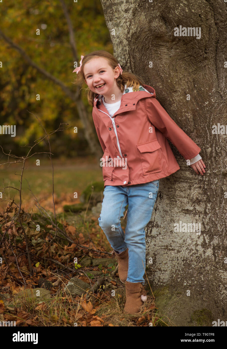 Little girl standing by tree laughing in autums Stock Photo - Alamy