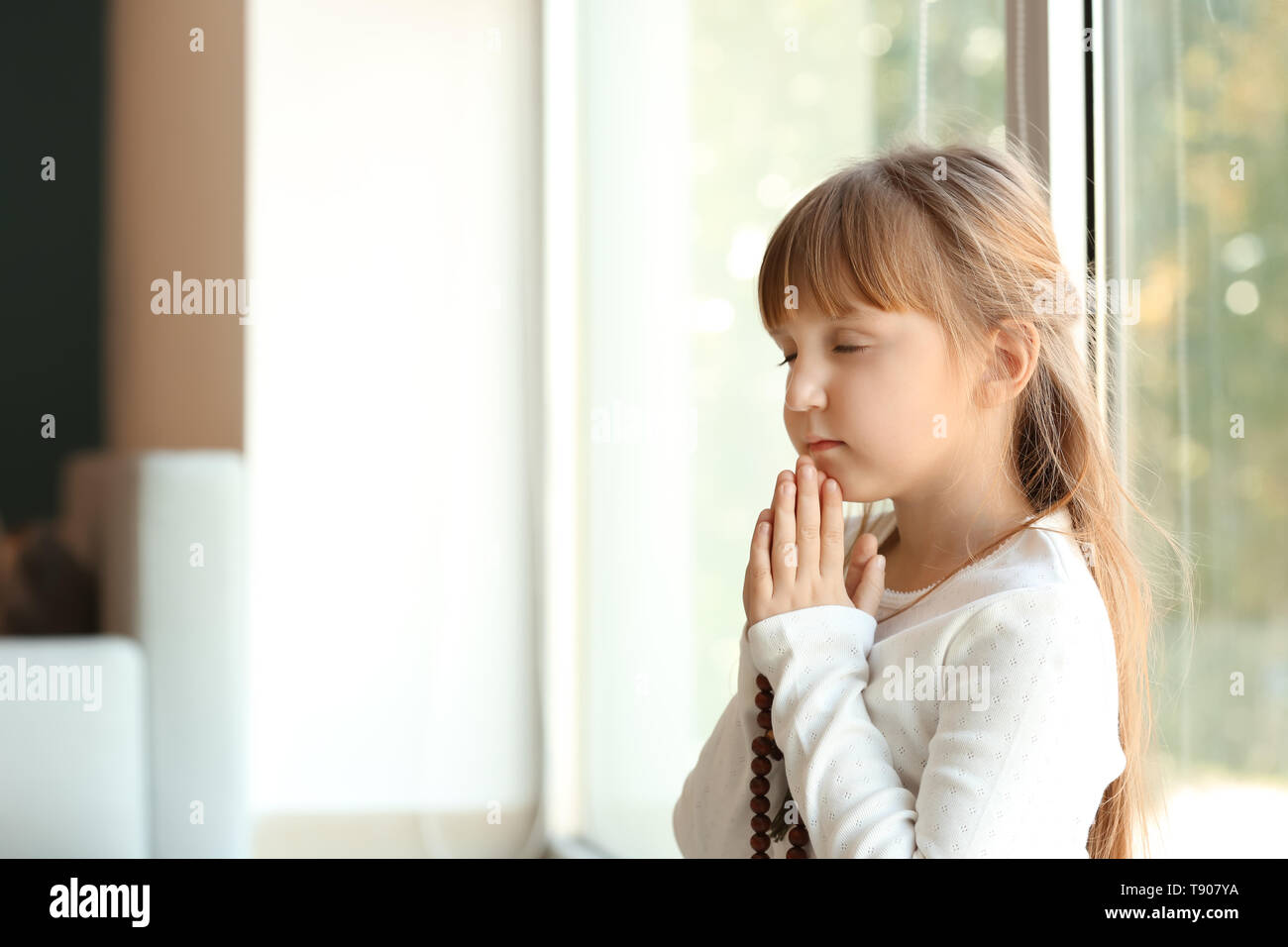 Little girl praying near window at home Stock Photo - Alamy