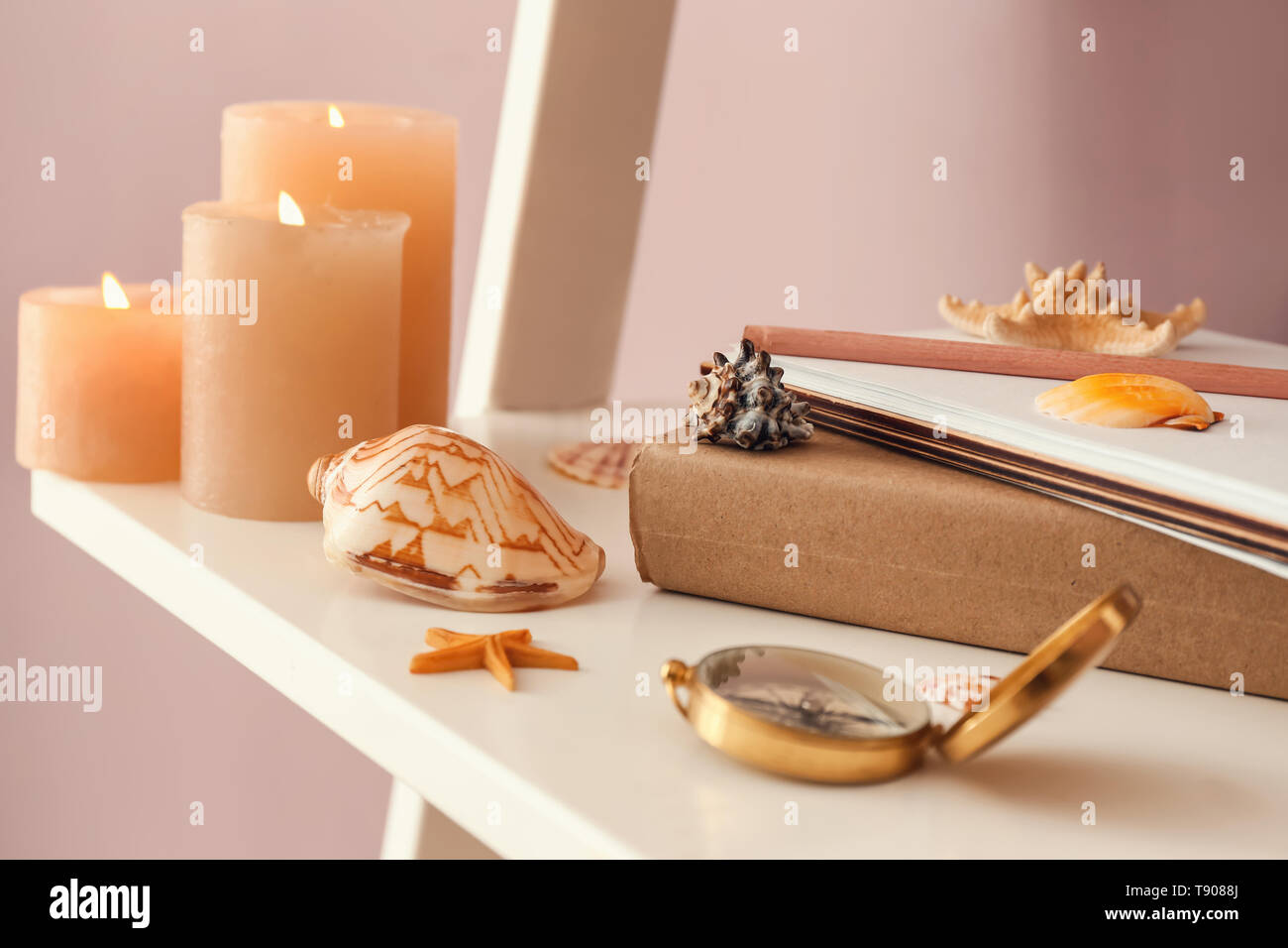 Sea shells with compass and burning candles on white shelf Stock Photo ...