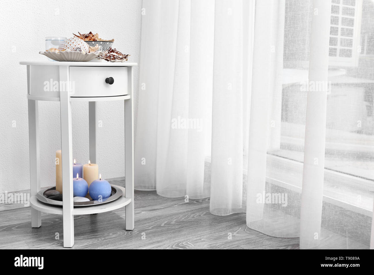 Different sea shells with burning candles on light table Stock Photo ...