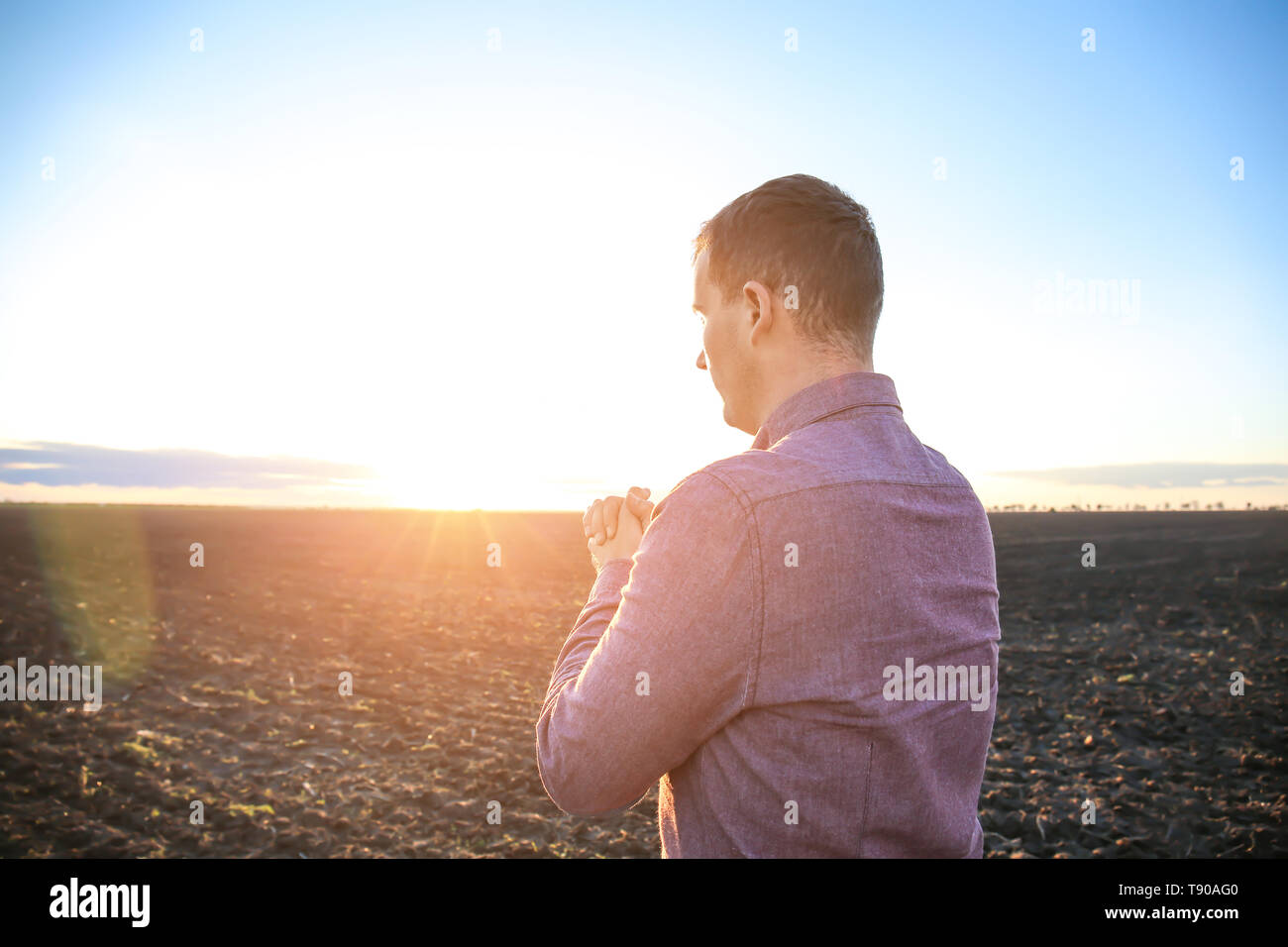 Religious man praying outdoors at sunset Stock Photo - Alamy