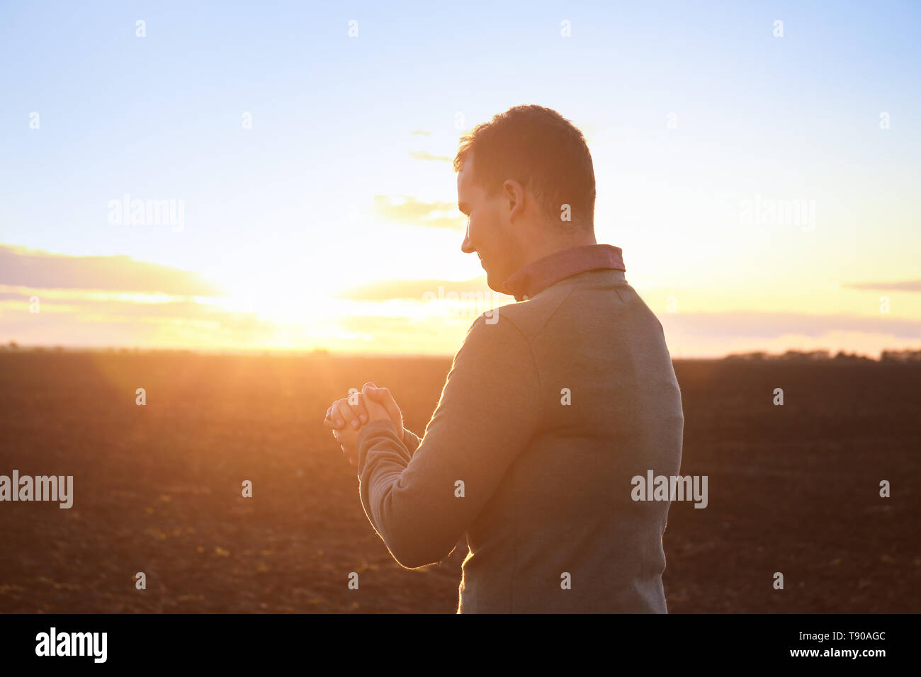 Religious man praying outdoors at sunset Stock Photo - Alamy