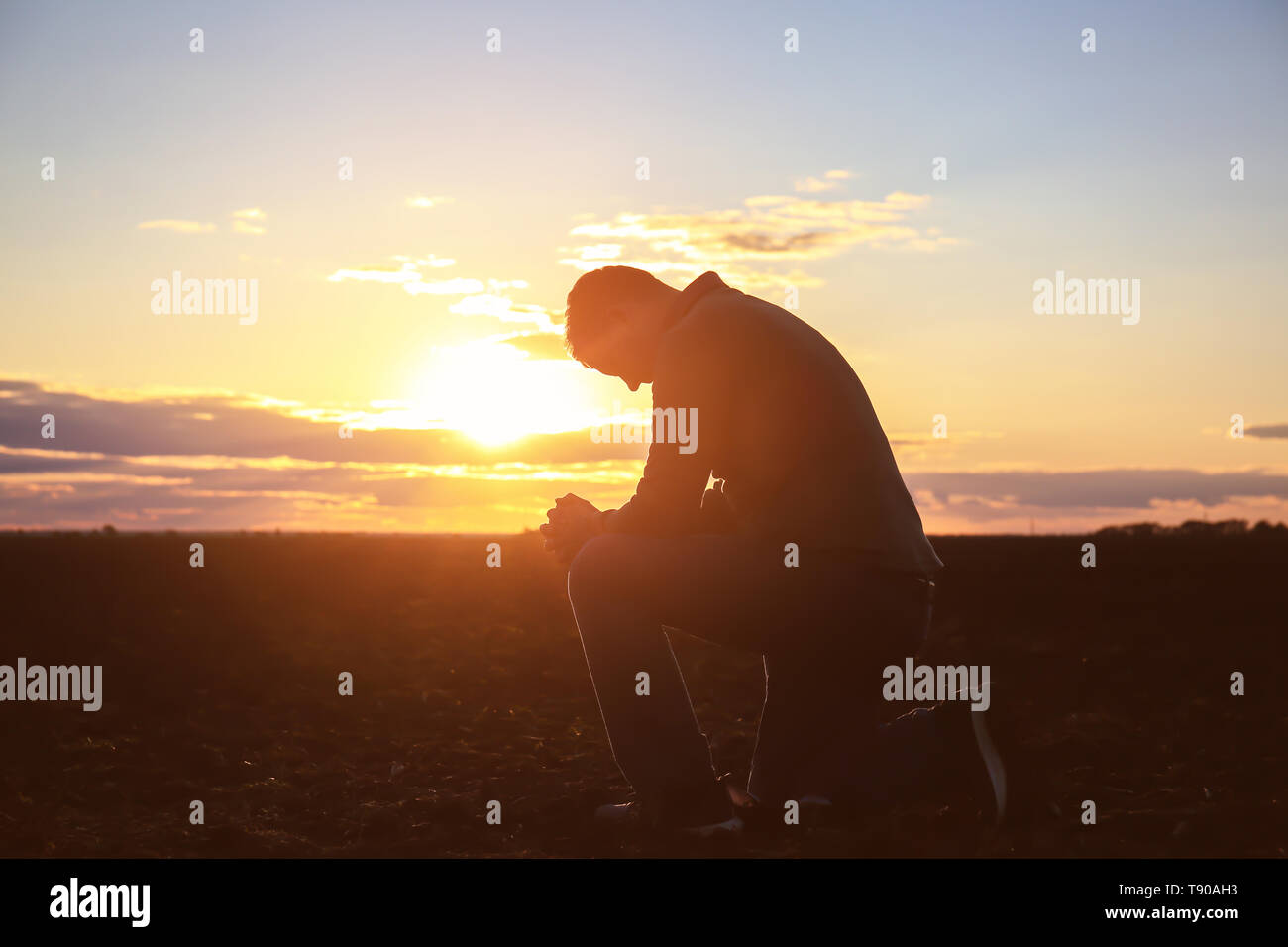 Religious man praying outdoors at sunset Stock Photo - Alamy