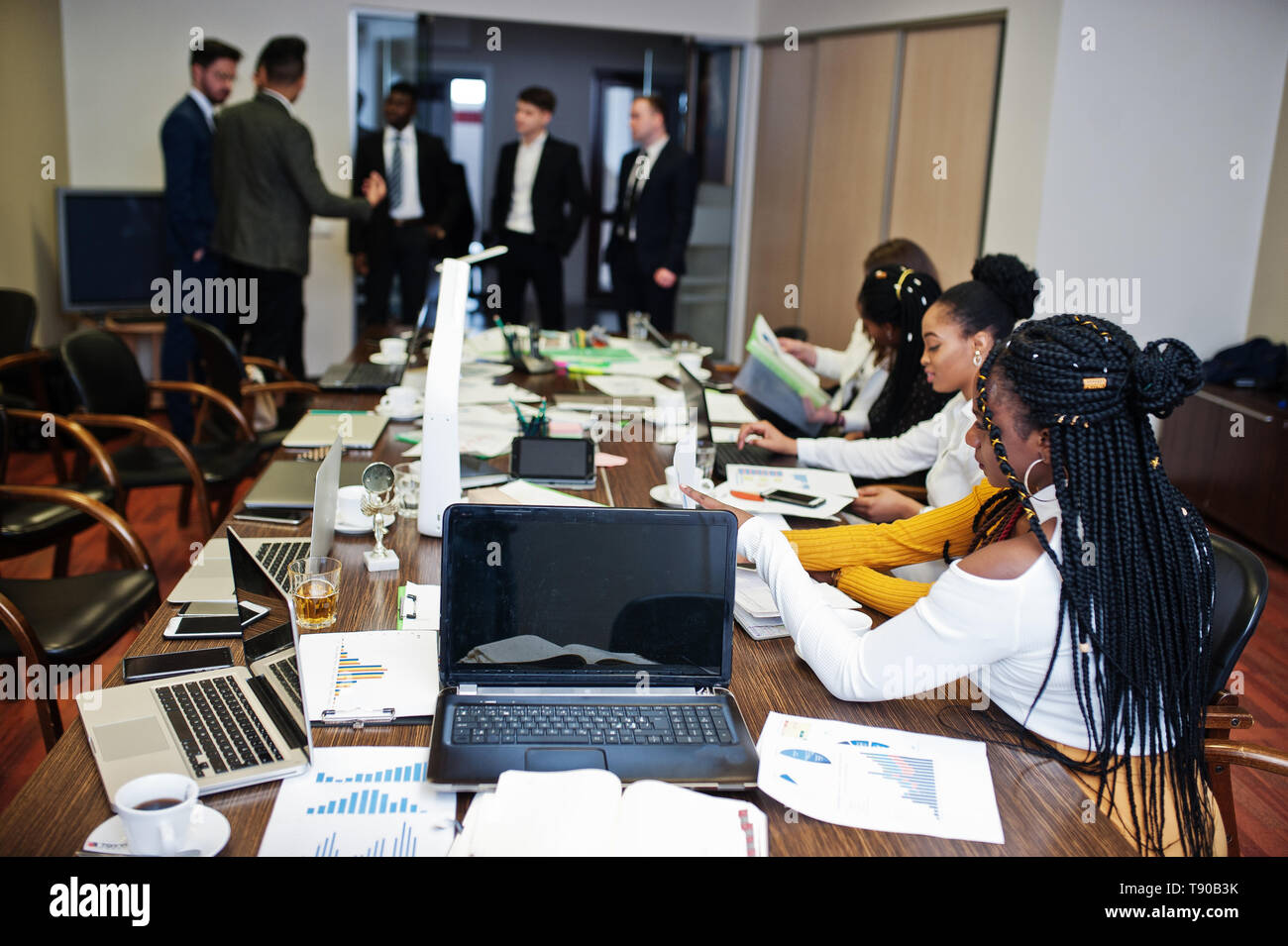 Multiracial business team addressing meeting around boardroom table ...