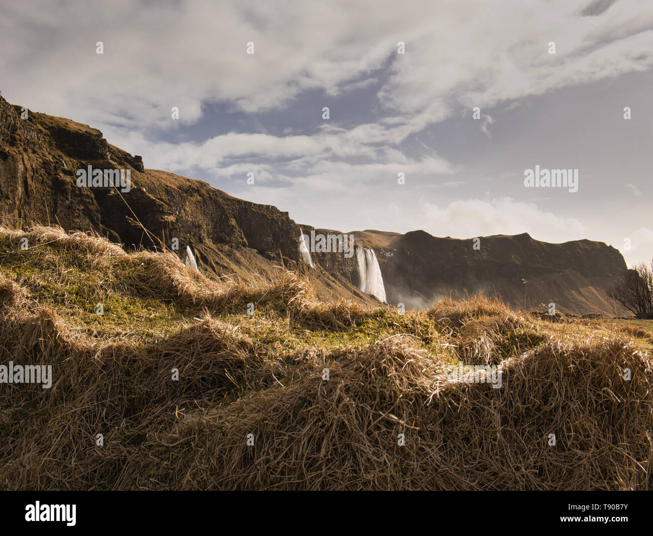 Small grassy hill with several waterfalls in the background Stock Photo ...