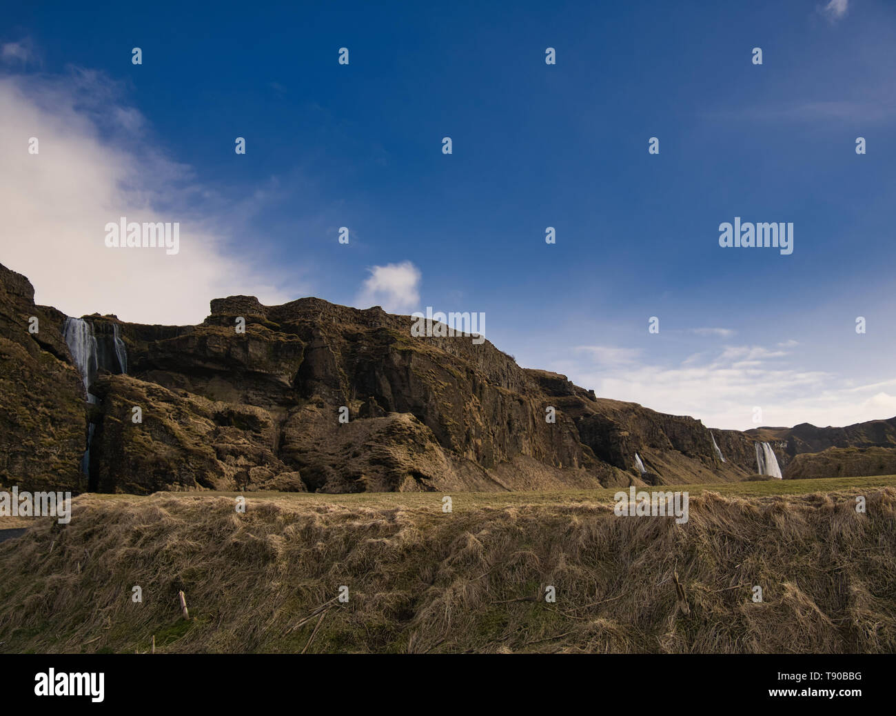 A small hill with several waterfalls in the background, along the ...