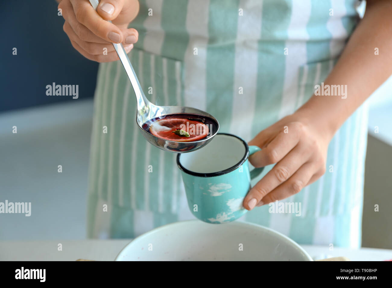 Woman pouring hot mulled wine from ladle into cup Stock Photo - Alamy