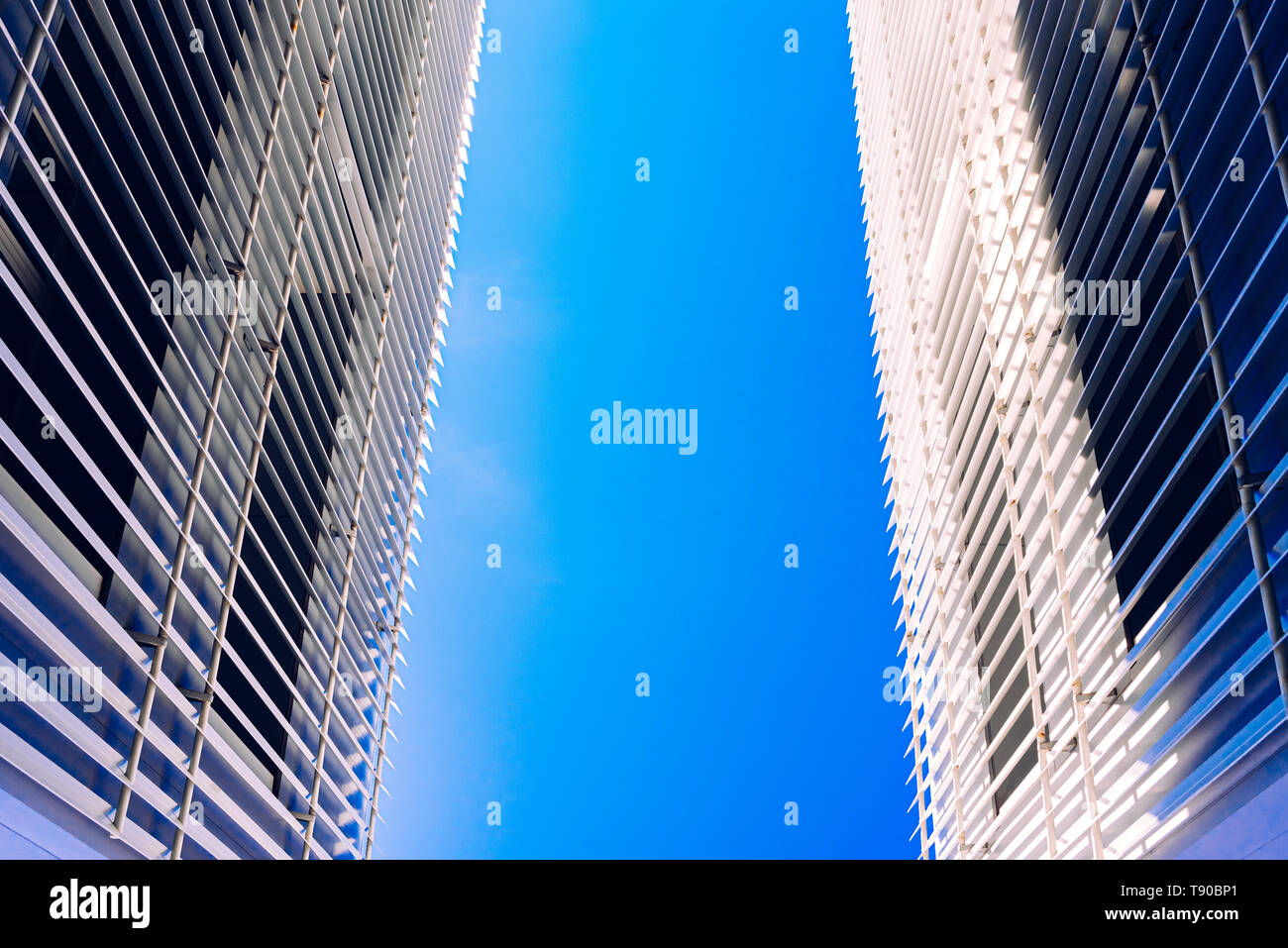 Two buildings converging on a blue sky background in the center Stock ...