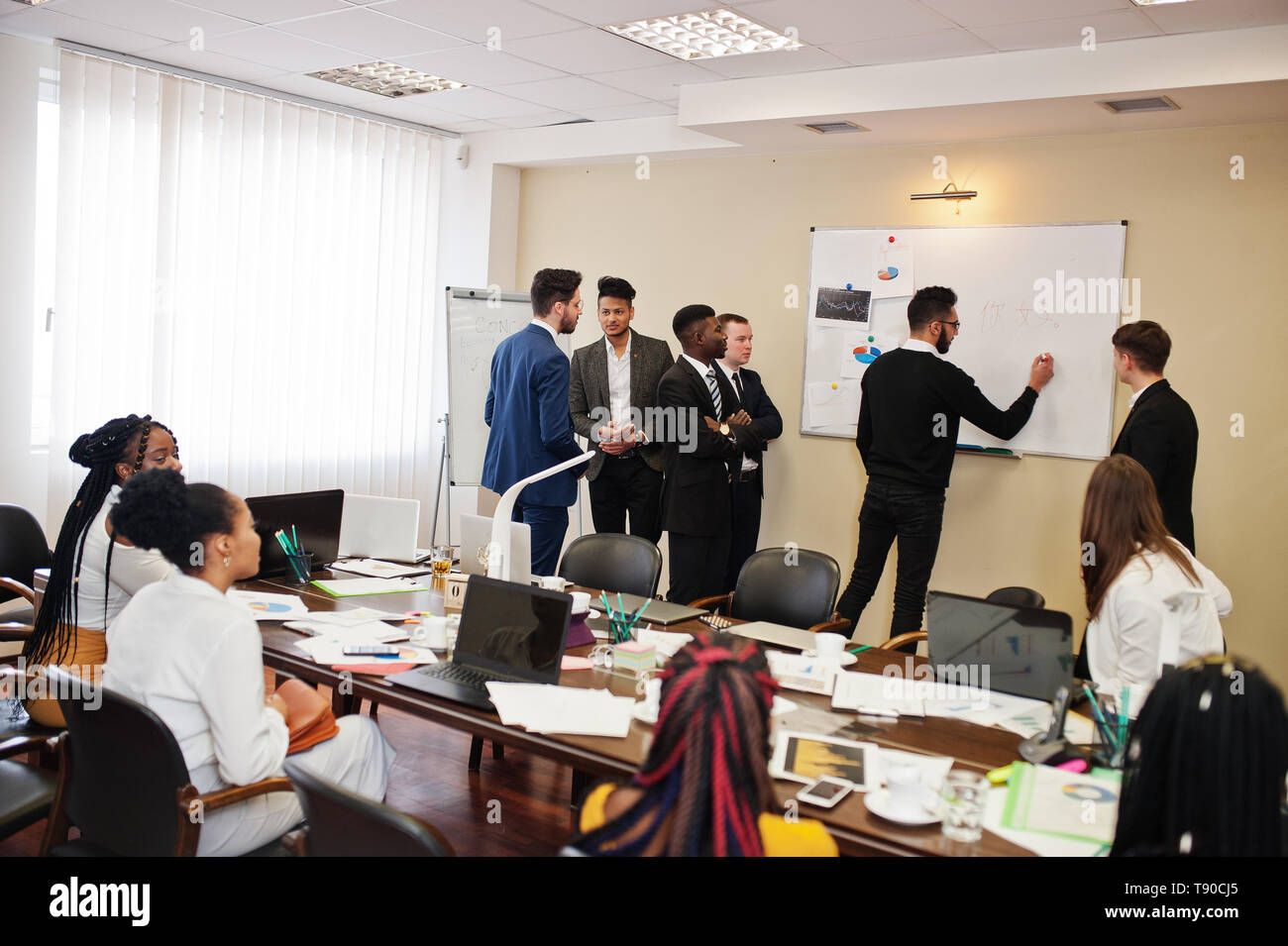 Multiracial business team addressing meeting around boardroom table and ...