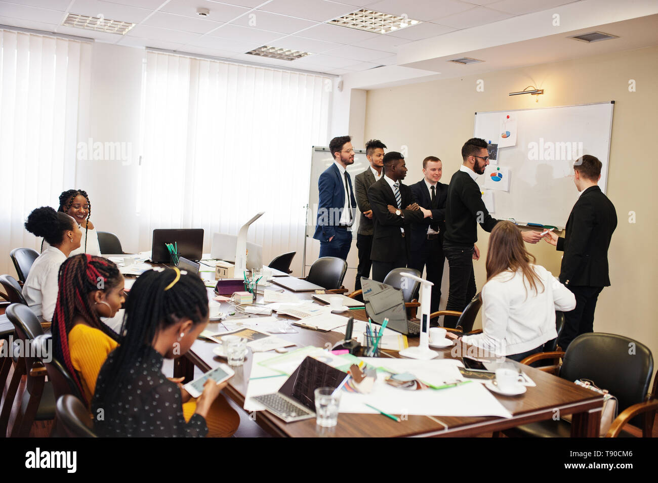Multiracial business team addressing meeting around boardroom table and ...