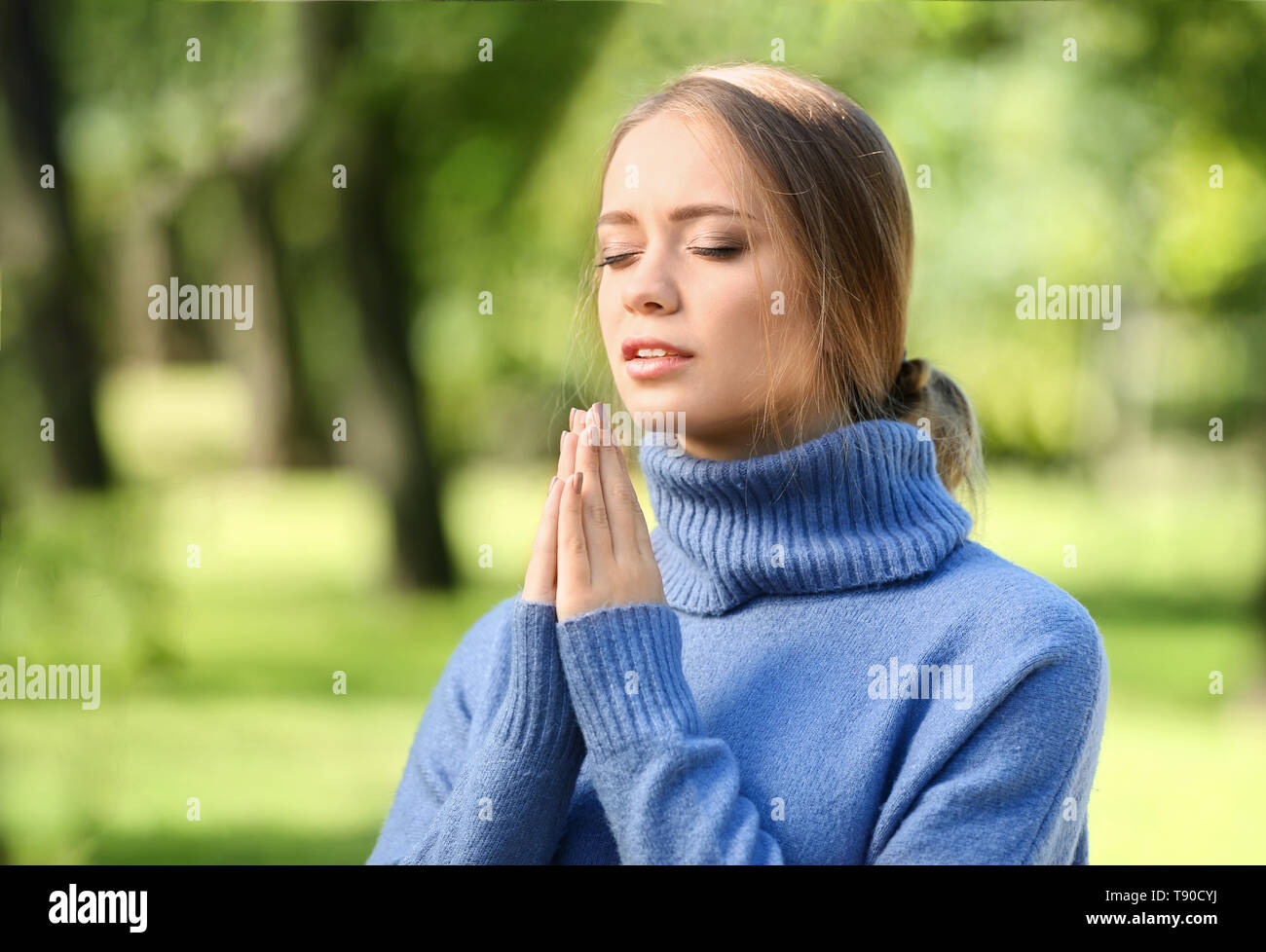 Beautiful young woman praying outdoors Stock Photo - Alamy