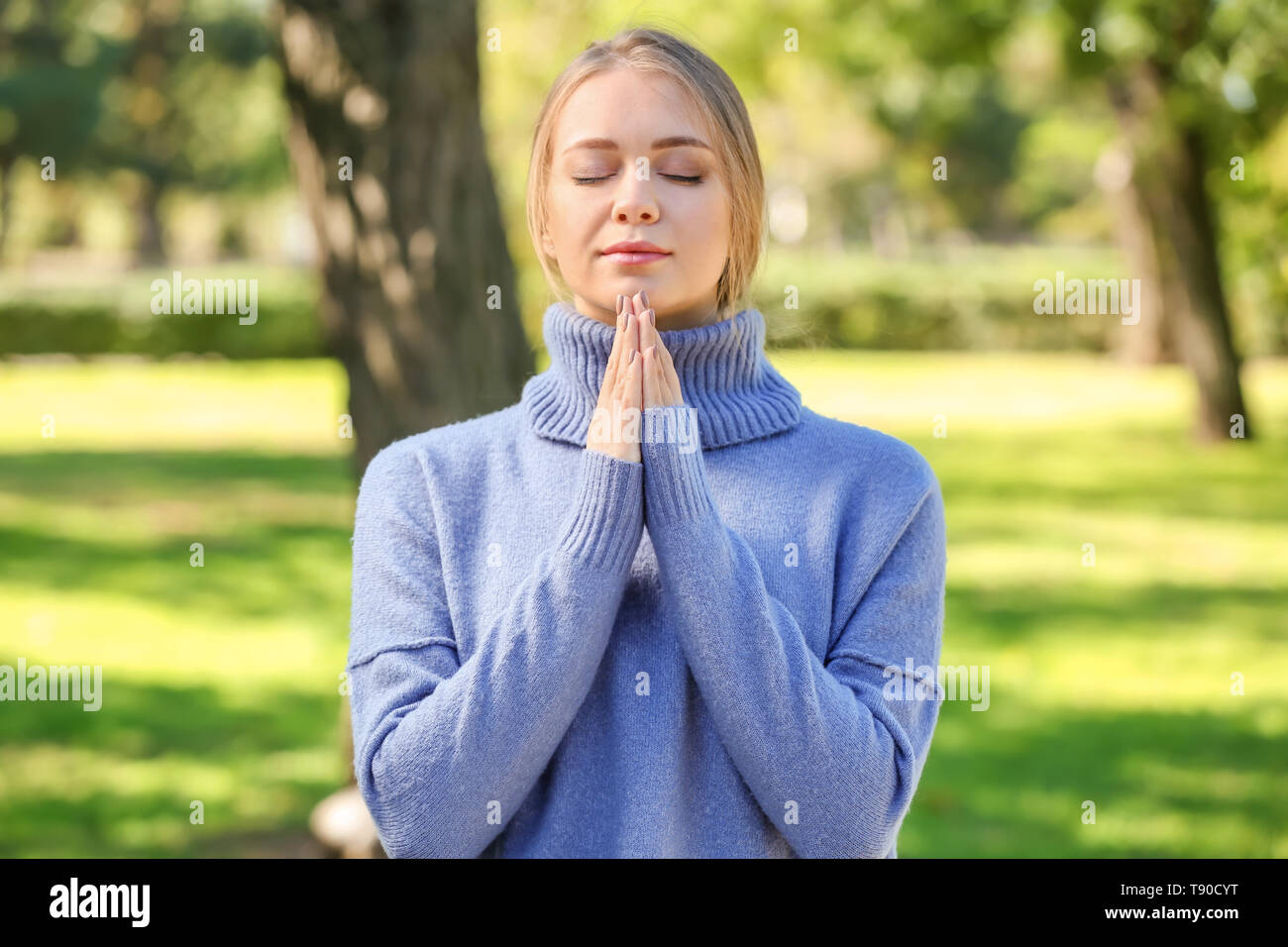 Beautiful young woman praying outdoors Stock Photo - Alamy