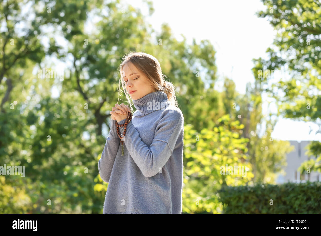 Beautiful young woman praying outdoors Stock Photo - Alamy