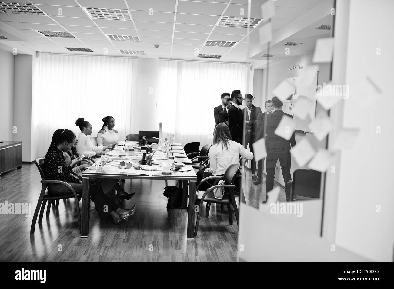 Multiracial business team addressing meeting around boardroom table and ...