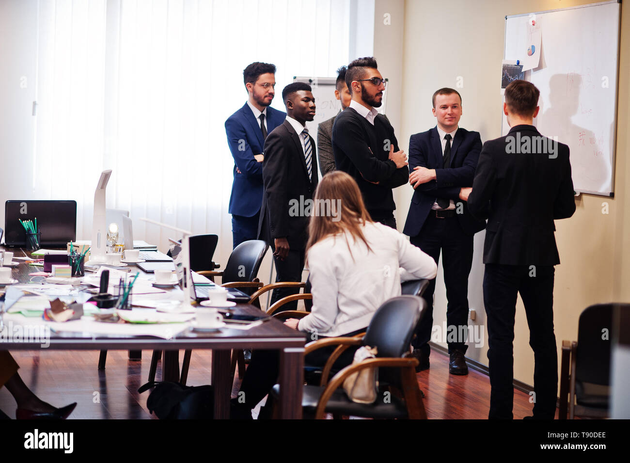 Multiracial business team addressing meeting around boardroom table and ...