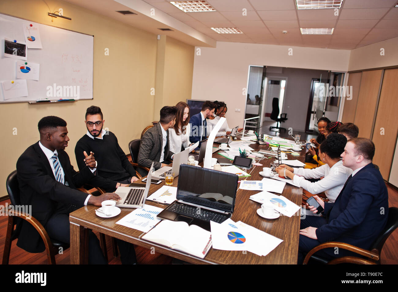Multiracial business team addressing meeting around boardroom table ...
