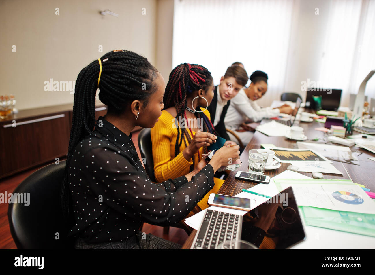Multiracial business team addressing meeting around boardroom table ...