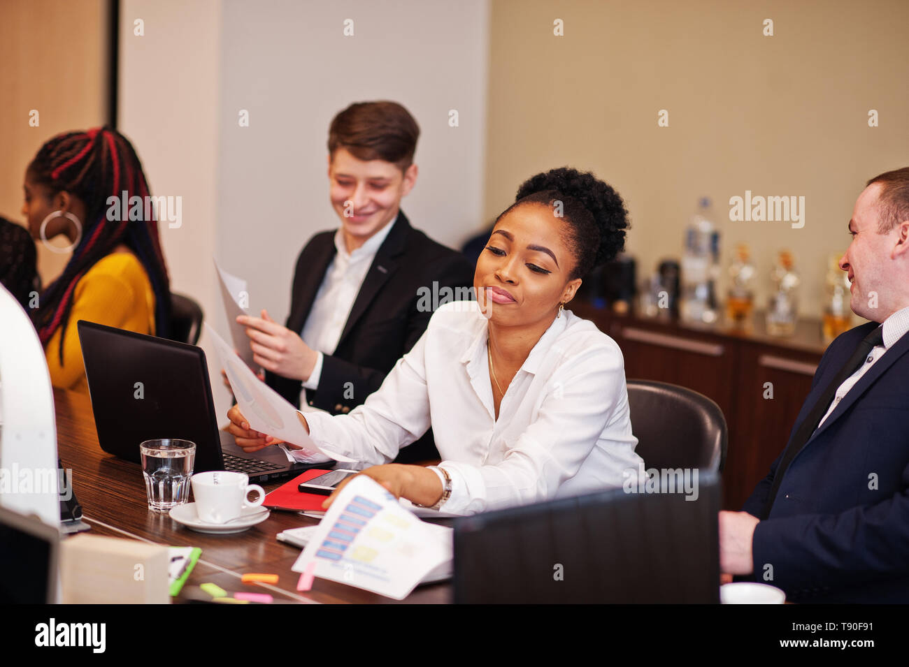 Multiracial business team addressing meeting around boardroom table ...