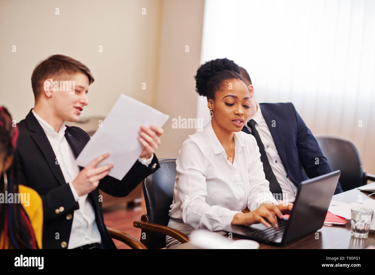 Multiracial business team addressing meeting around boardroom table ...