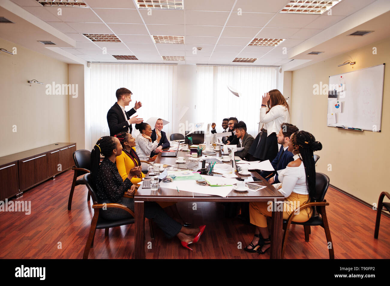 Multiracial business team meeting around boardroom table, two team ...
