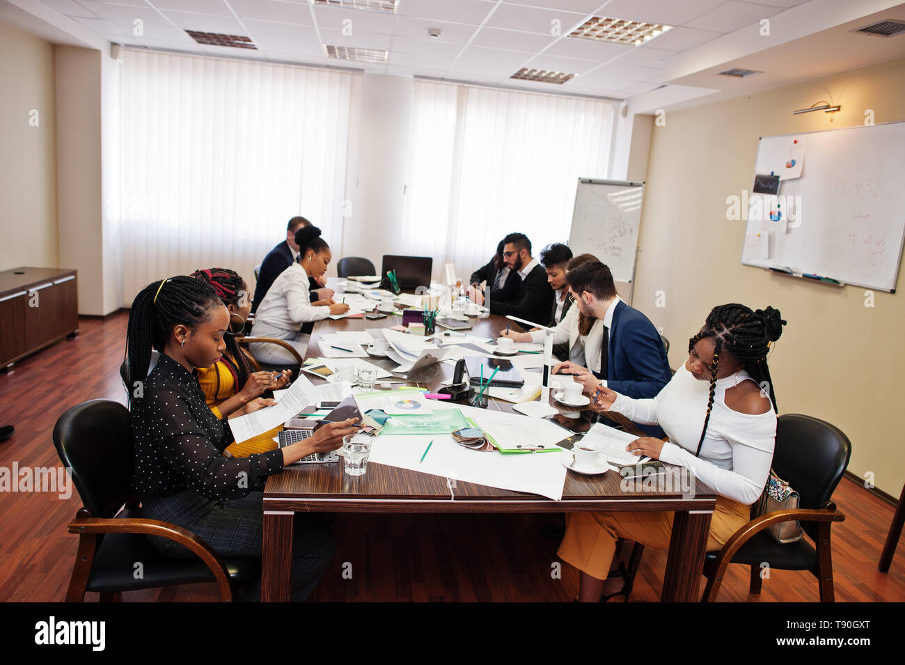 Multiracial business team addressing meeting around boardroom table ...