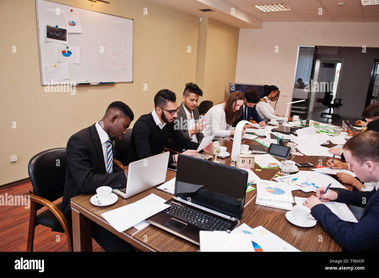 Multiracial business team addressing meeting around boardroom table ...